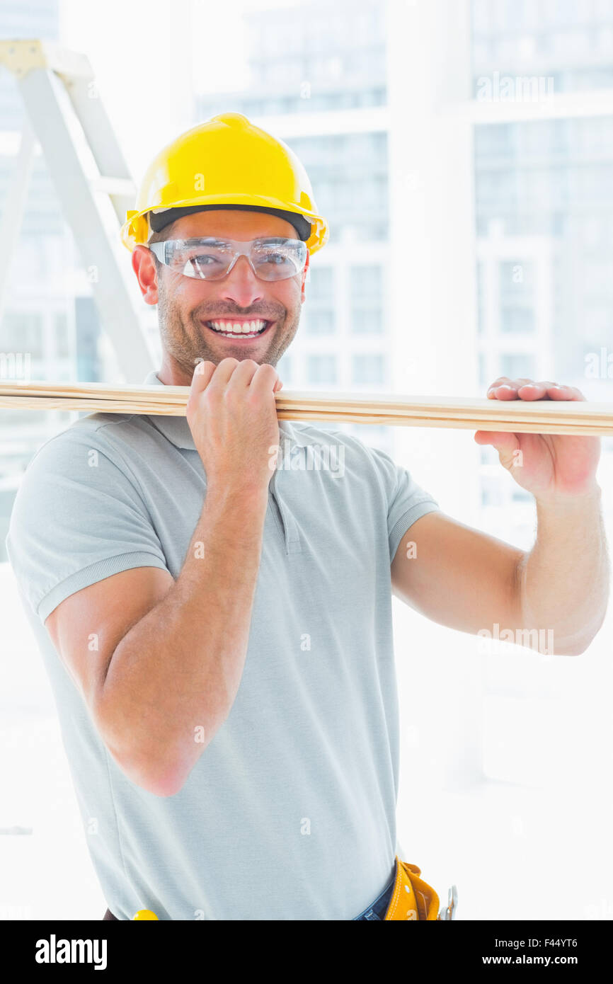 Happy carpenter carrying wood in building Stock Photo - Alamy