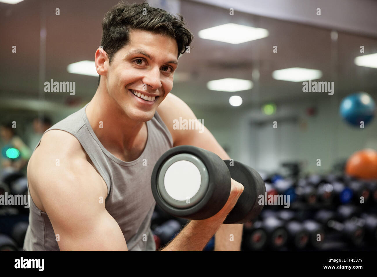 Smiling man lifting dumbbell weight Stock Photo - Alamy