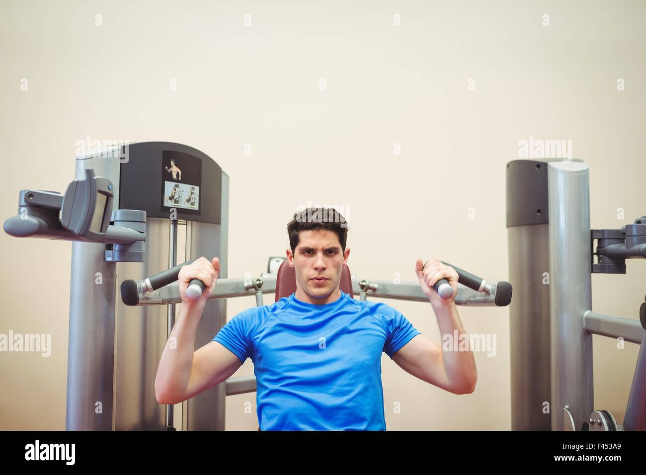 Fit man using weights machine for arms Stock Photo - Alamy