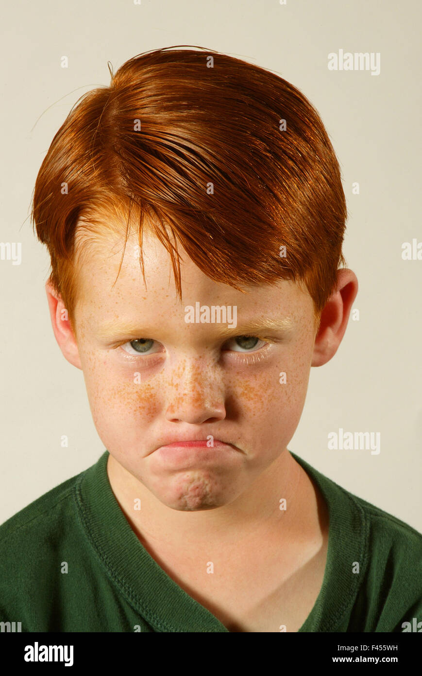 Modeling a frown, a self confident red-headed five year old boy poses ...