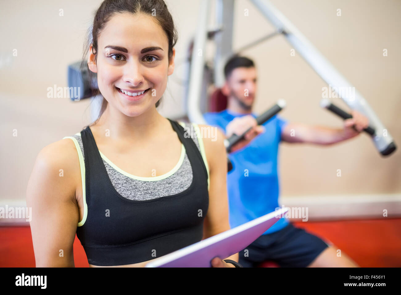 Trainer working with athlete at weights machine Stock Photo - Alamy