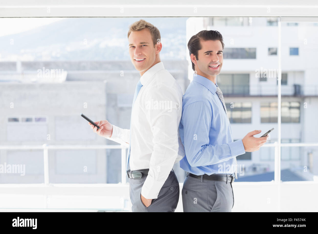 Two businessmen standing back to back Stock Photo - Alamy