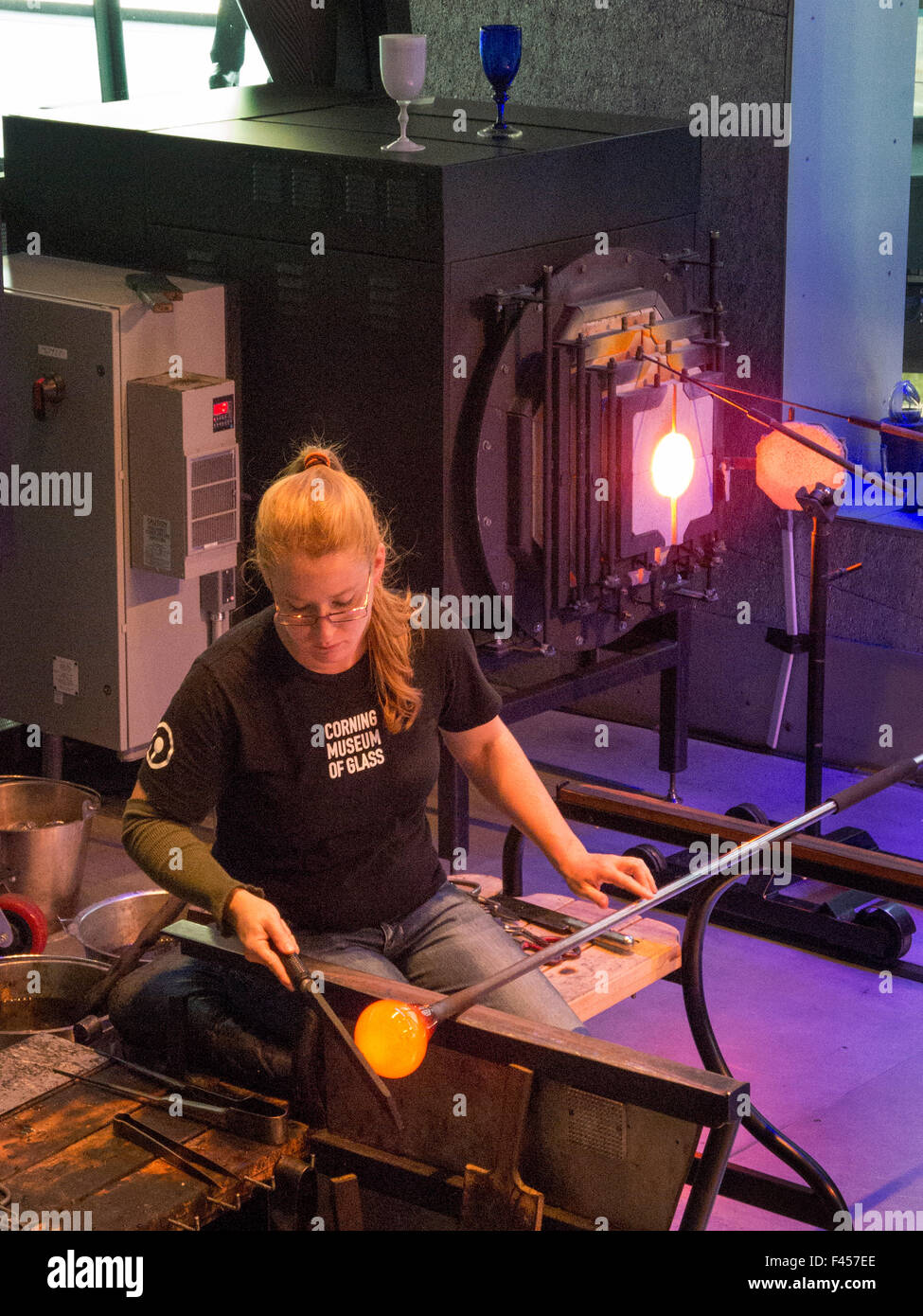 Using an insulated tool, a glassblower or gaffer shapes molten glass on ...