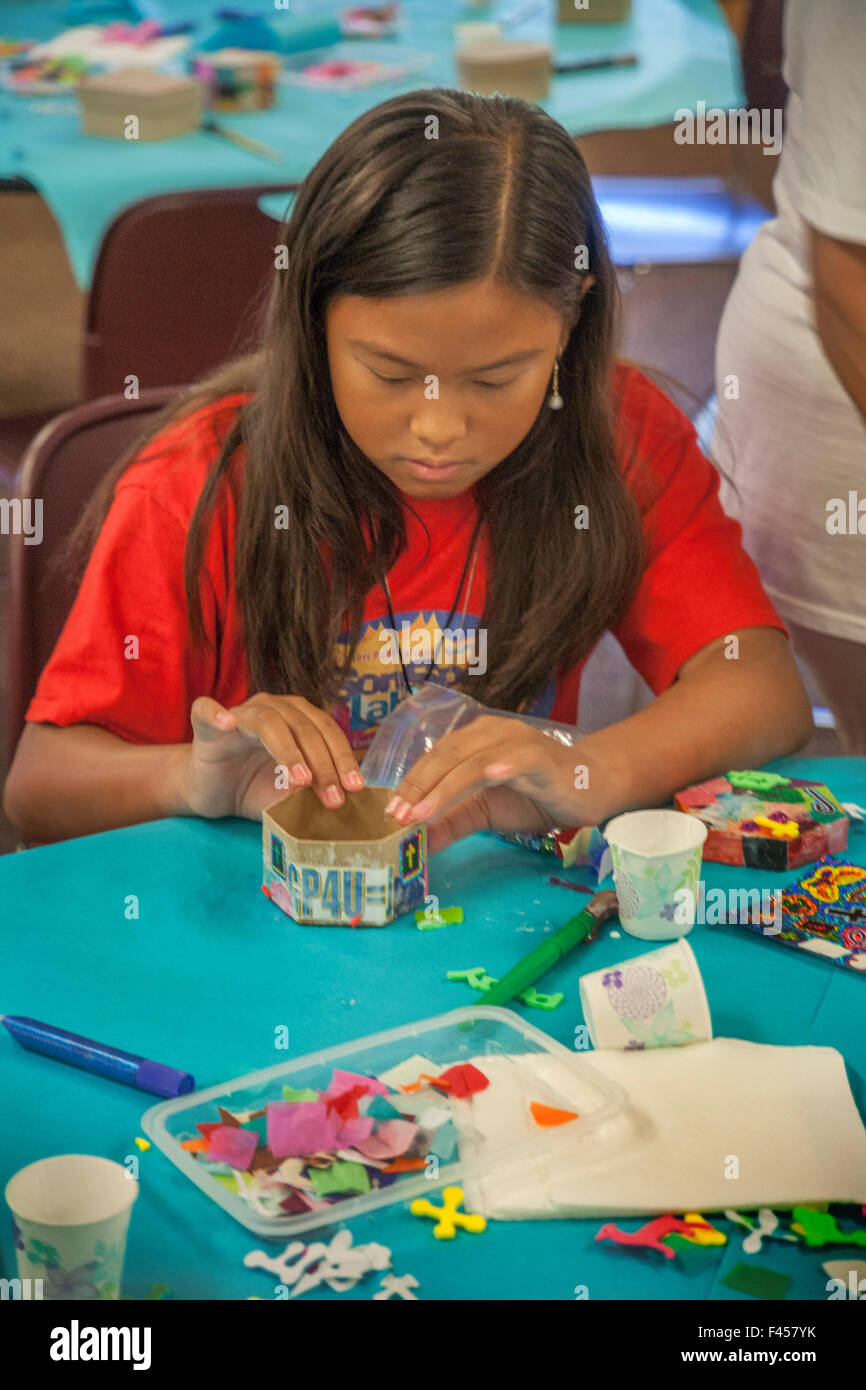 An Asian American girl assembles a prayer box in crafts class at a ...