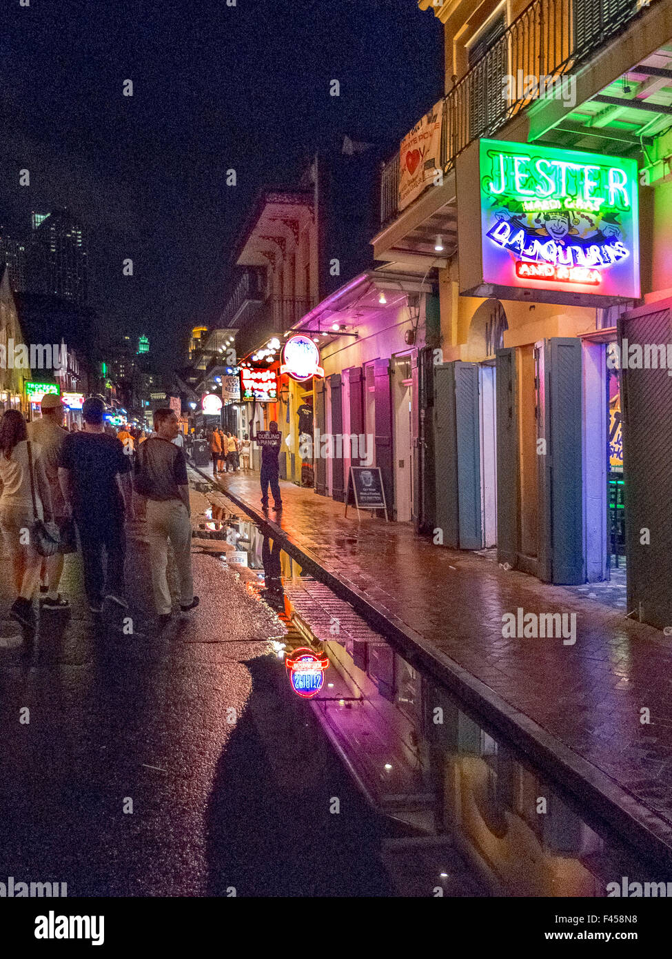 Wet sidewalks reflect garish signs on a rainy night on Bourbon Street ...