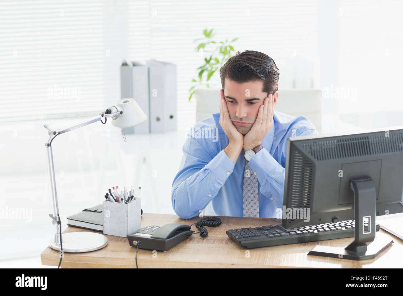 Sad businessman sitting at his desk Stock Photo - Alamy
