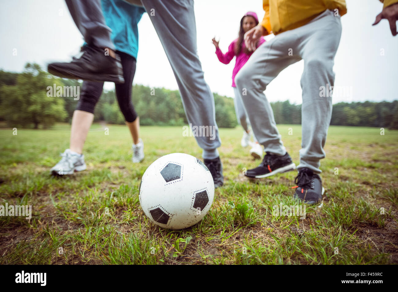 Friends running towards football Stock Photo - Alamy