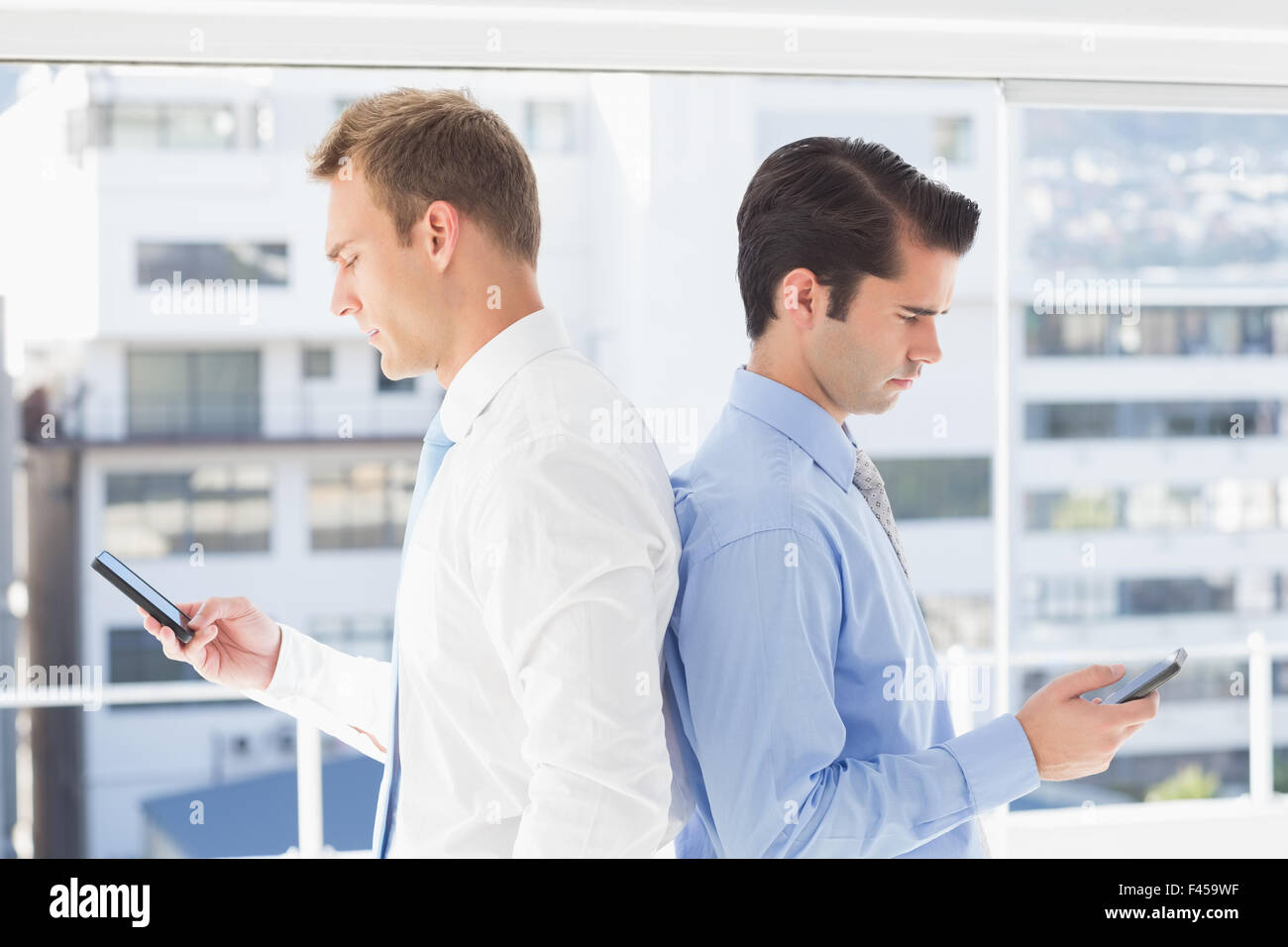 Two businessmen standing back to back Stock Photo - Alamy