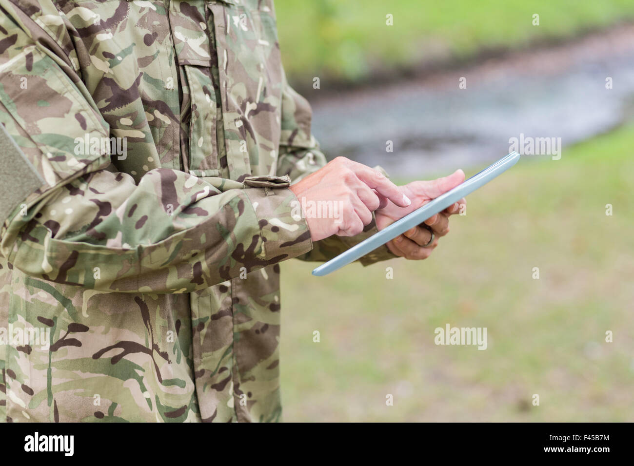Soldier looking at tablet pc in park Stock Photo - Alamy