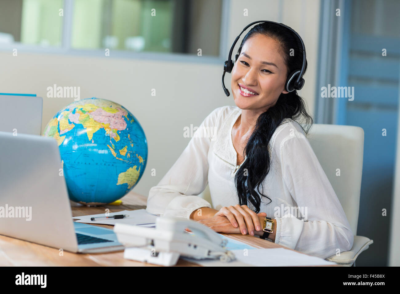 Pretty travel agent smiling at camera Stock Photo - Alamy