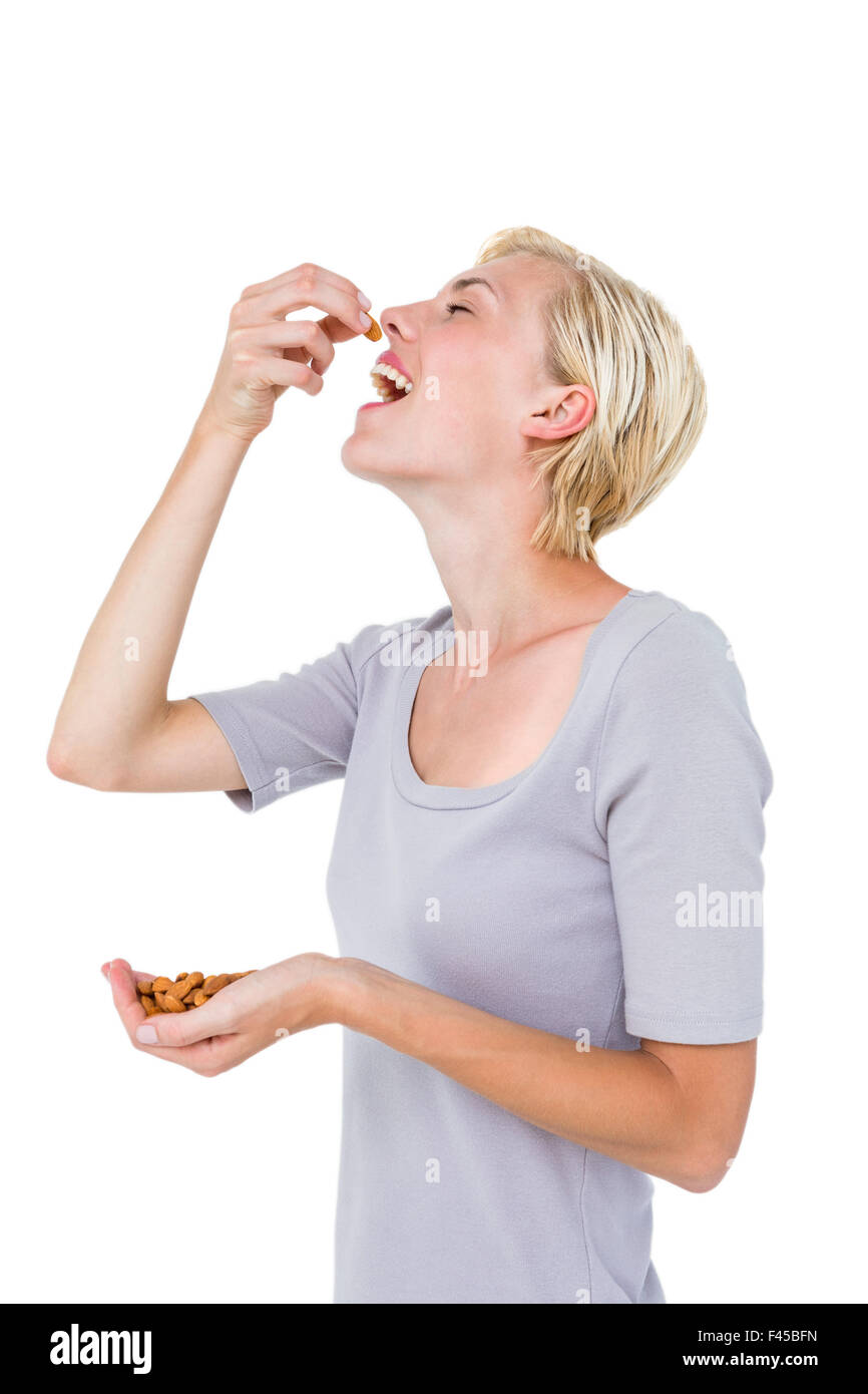 Happy blonde woman eating almond nuts Stock Photo - Alamy