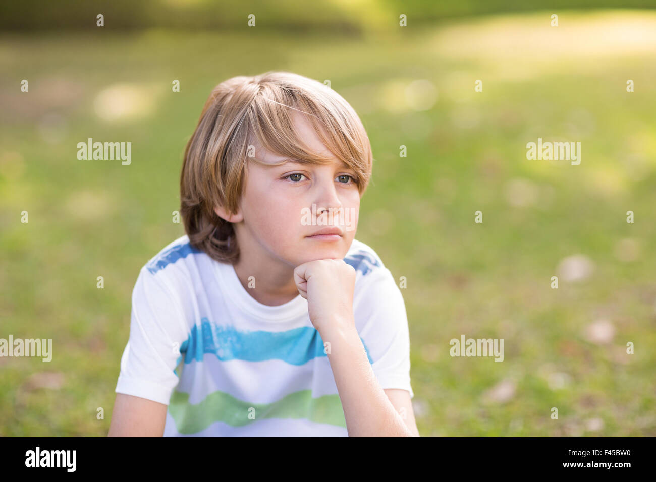 Little boy thinking in a park Stock Photo - Alamy