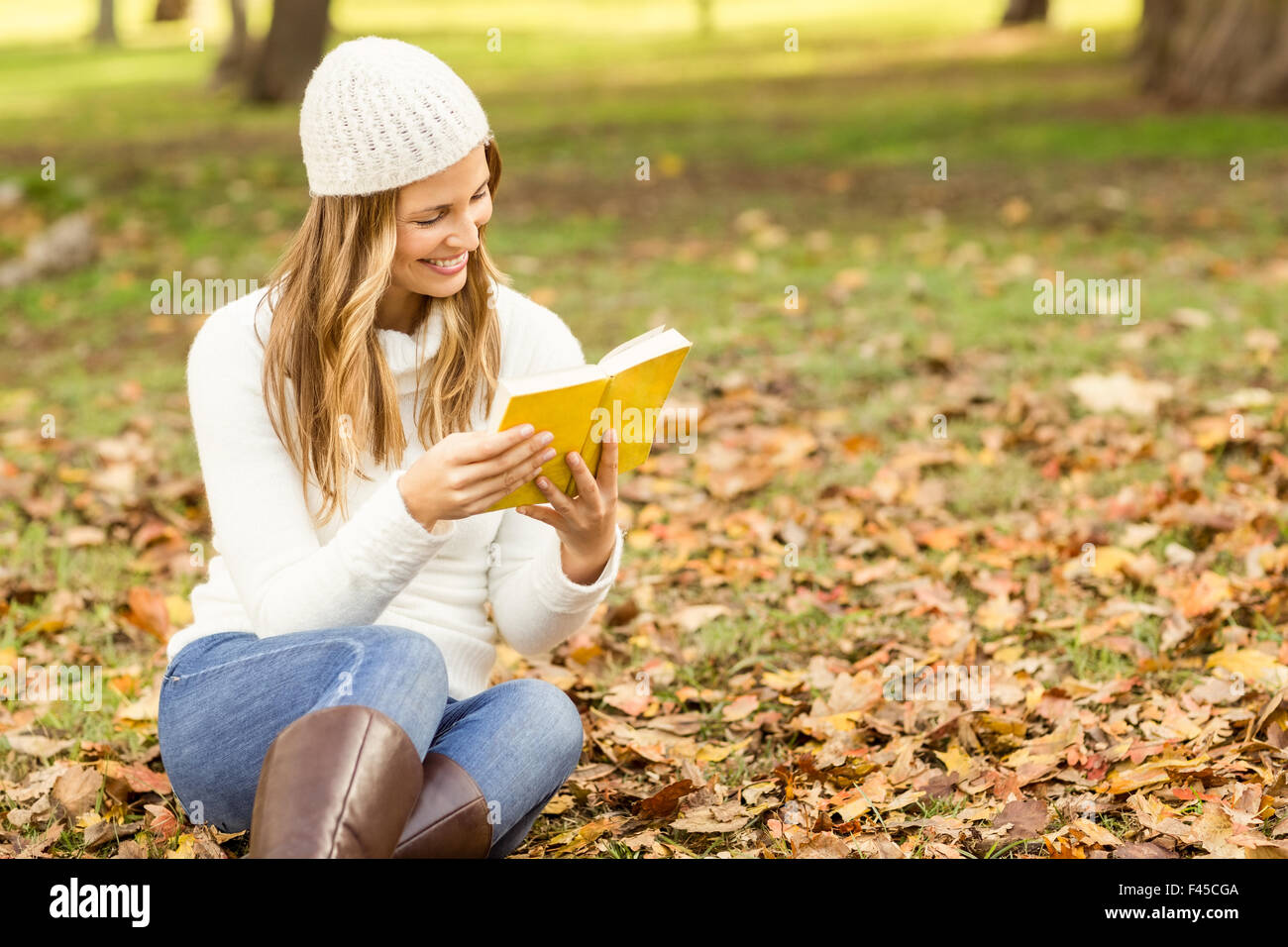 Smiling pretty woman reading a book in leaves Stock Photo - Alamy