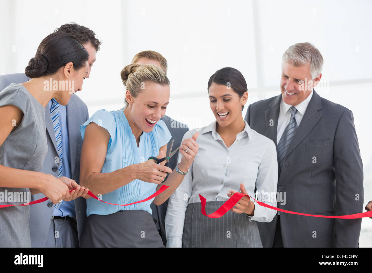 Happy business team cutting red ribbon Stock Photo - Alamy