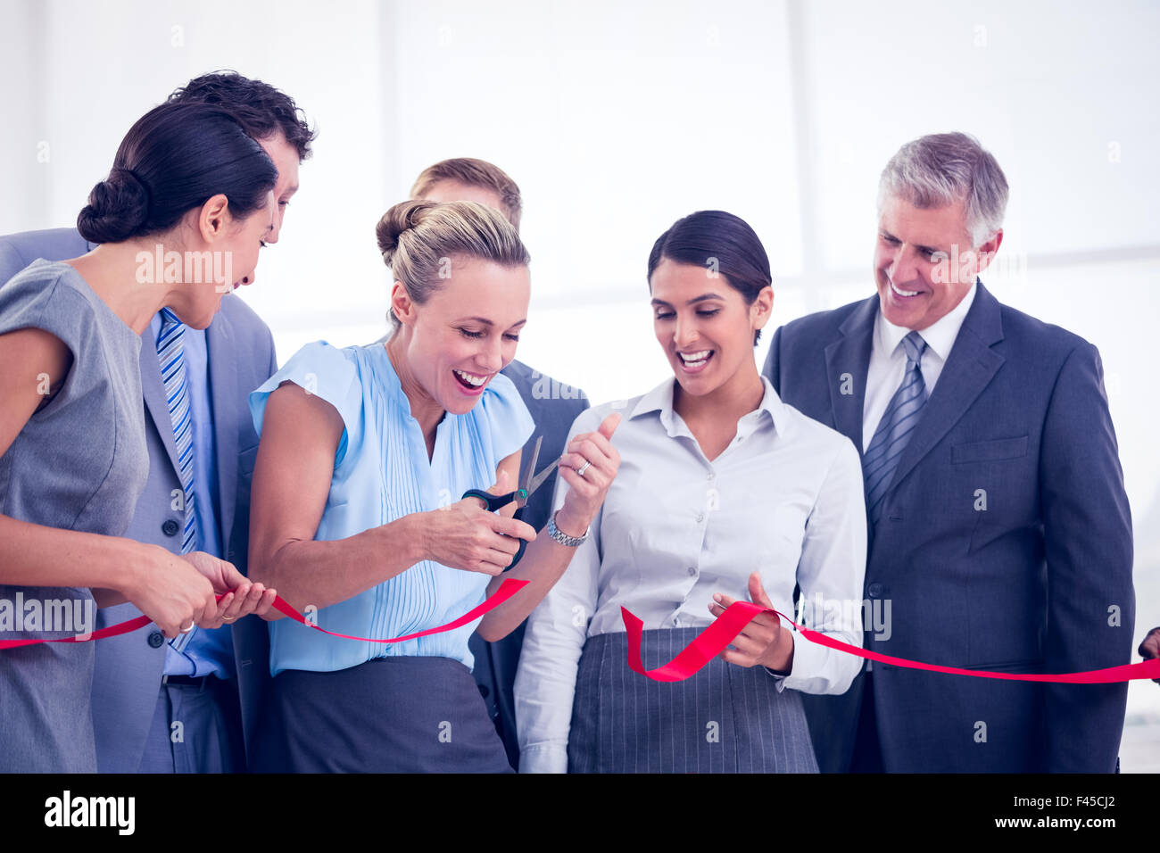 Happy business team cutting red ribbon Stock Photo - Alamy