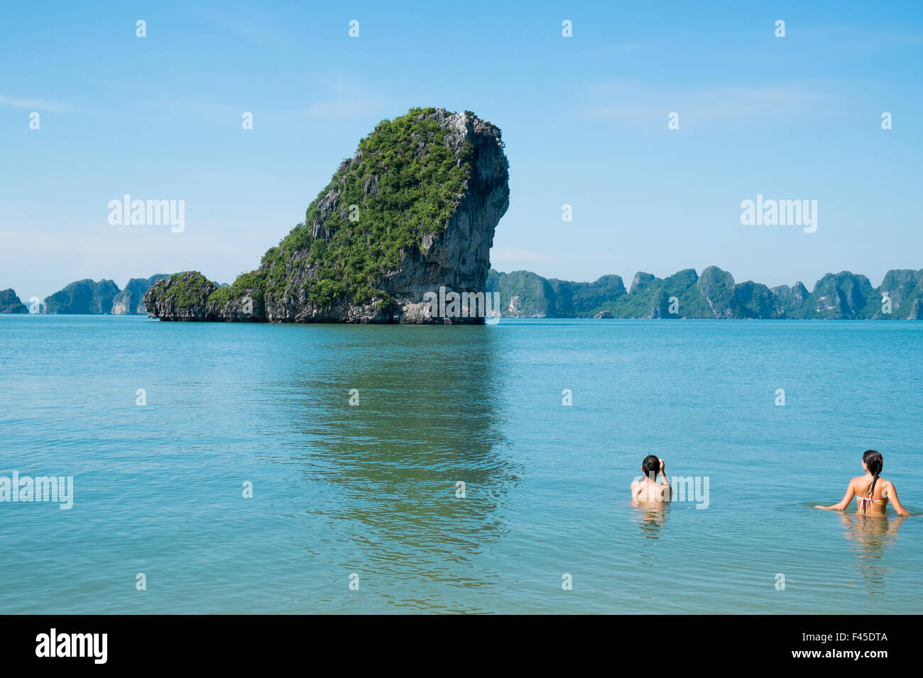 Young couple swim in the waters around Cong Do island in Ha long bay, a ...