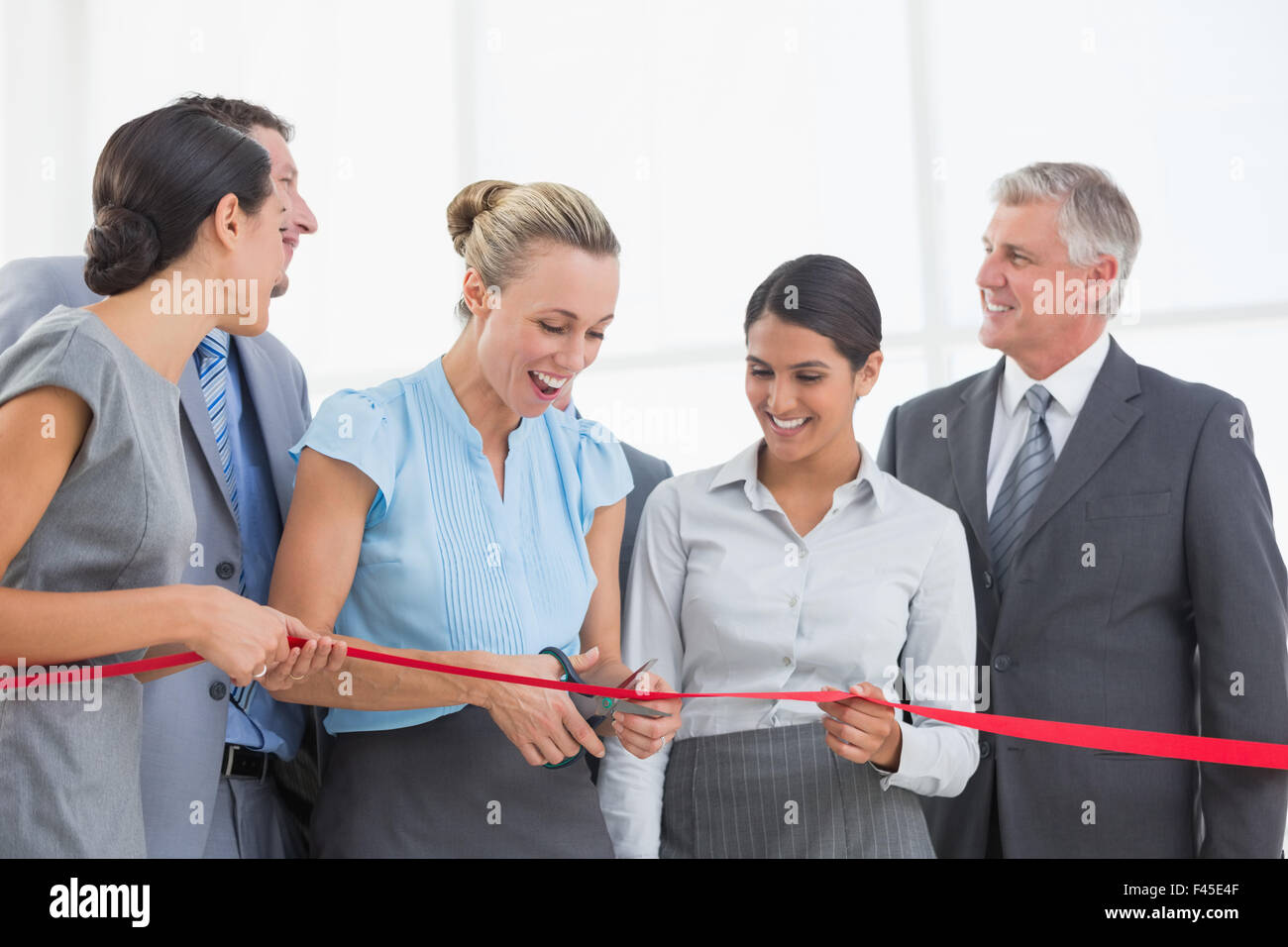 Happy business team cutting red ribbon Stock Photo - Alamy