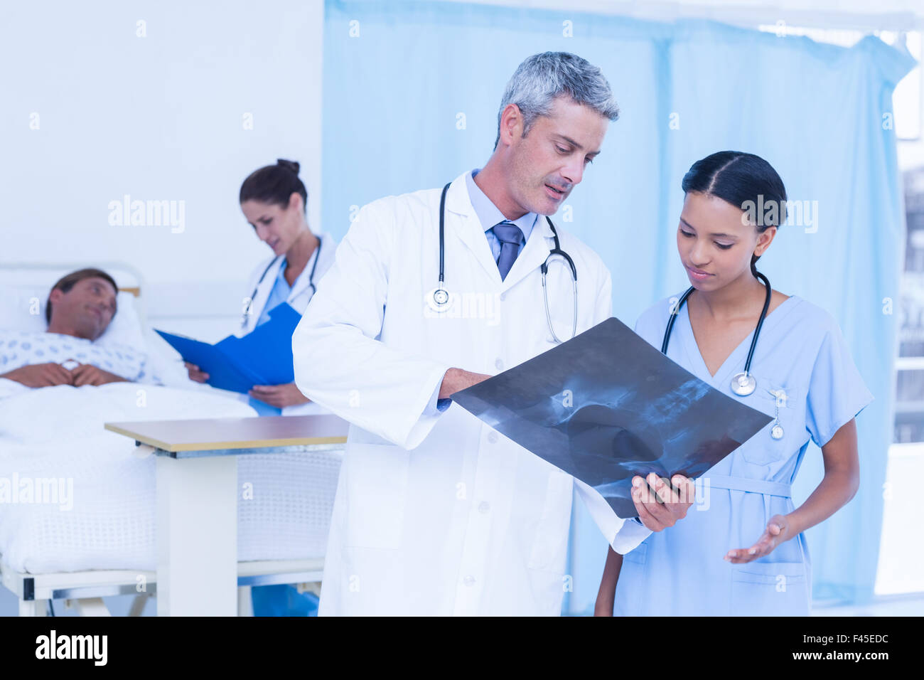 Doctor with colleague and patient behind Stock Photo - Alamy