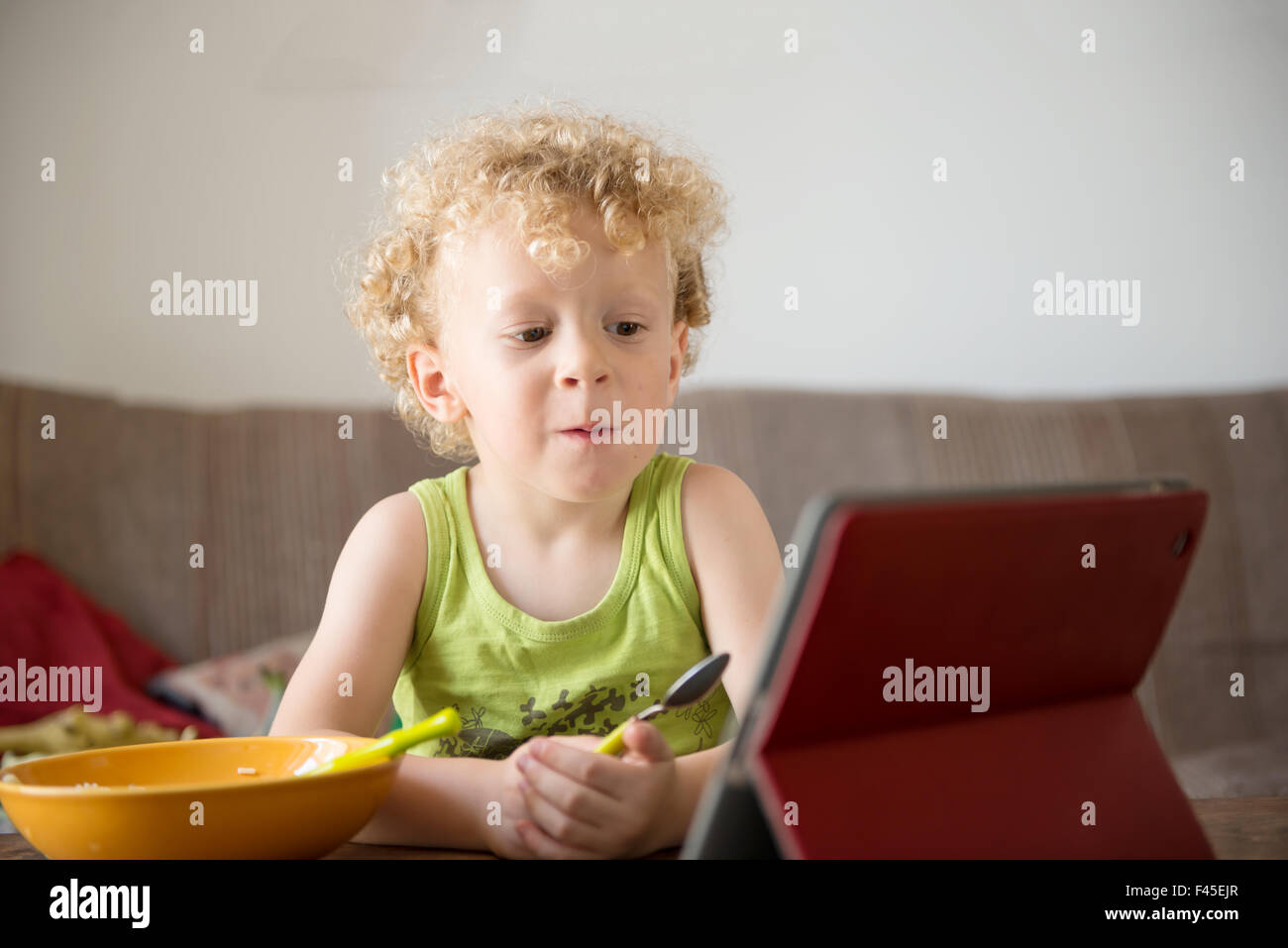 a young child eats while watching a digital tablet Stock Photo - Alamy