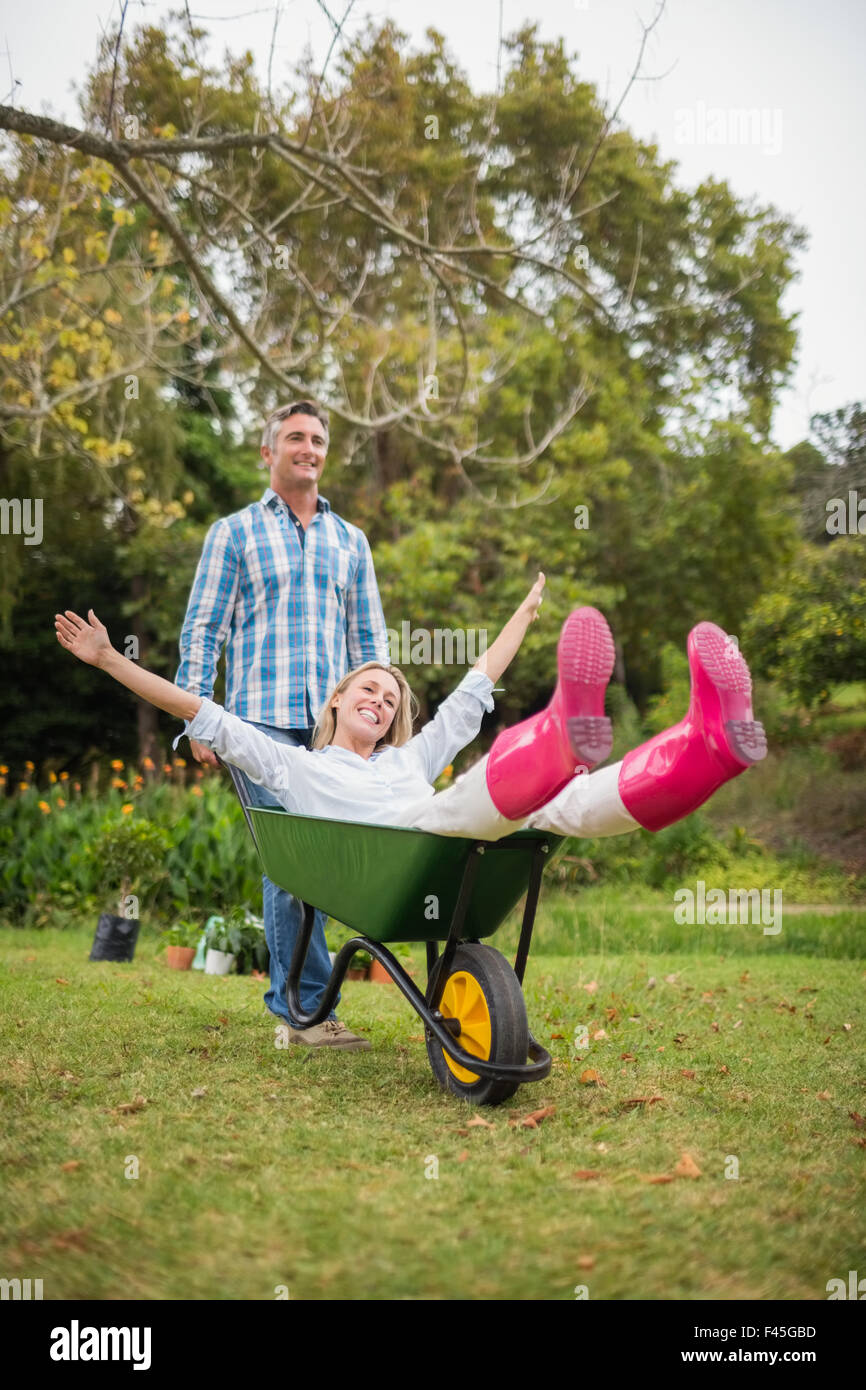 Happy couple playing with a wheelbarrow Stock Photo - Alamy