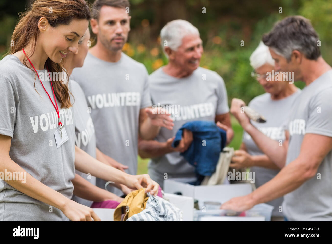 Happy volunteer looking at donation box Stock Photo - Alamy