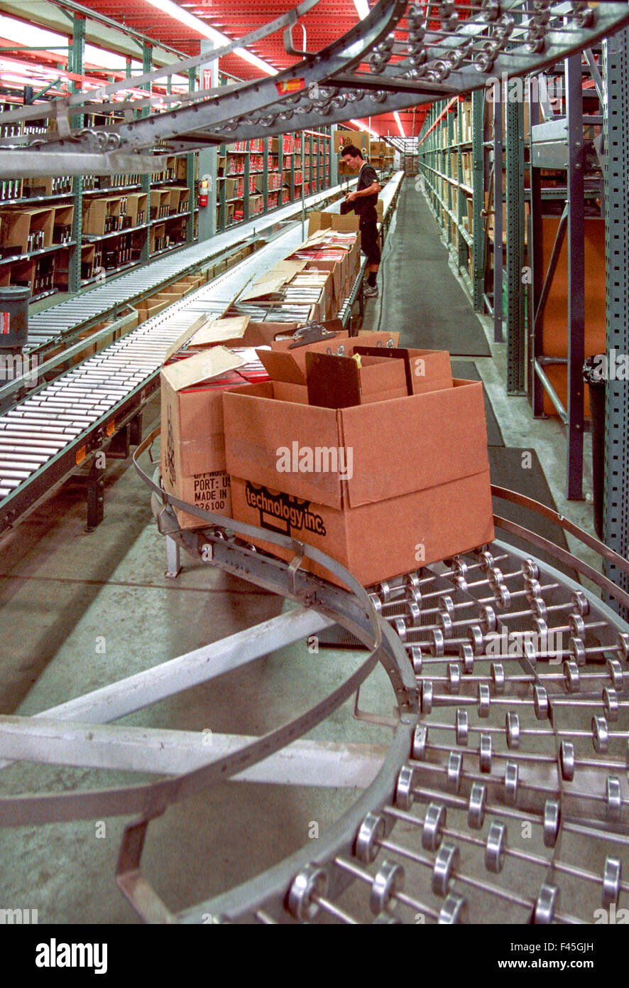 A cardboard box of merchandise rolls down a wheeled conveyer in an ...