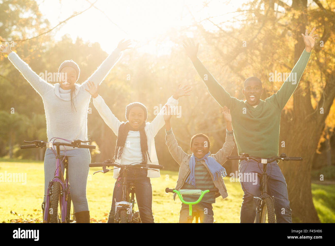 Young smiling family doing a bike ride with arms raised Stock Photo - Alamy