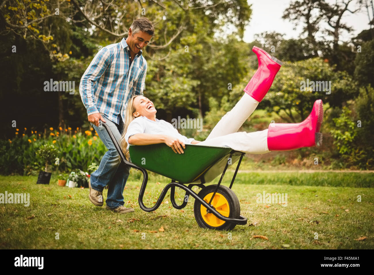 Happy couple playing with a wheelbarrow Stock Photo - Alamy