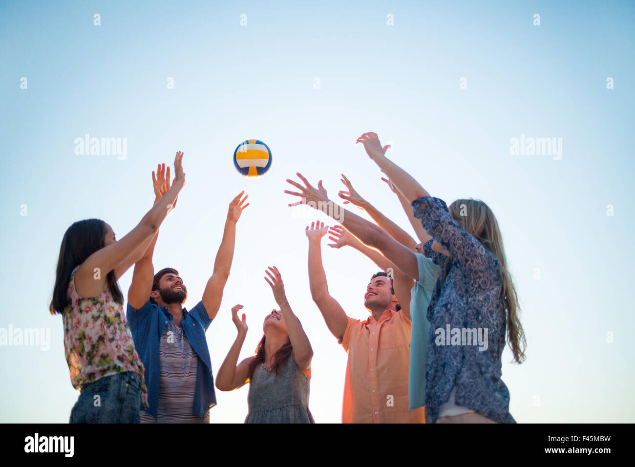 Happy friends throwing volleyball Stock Photo - Alamy