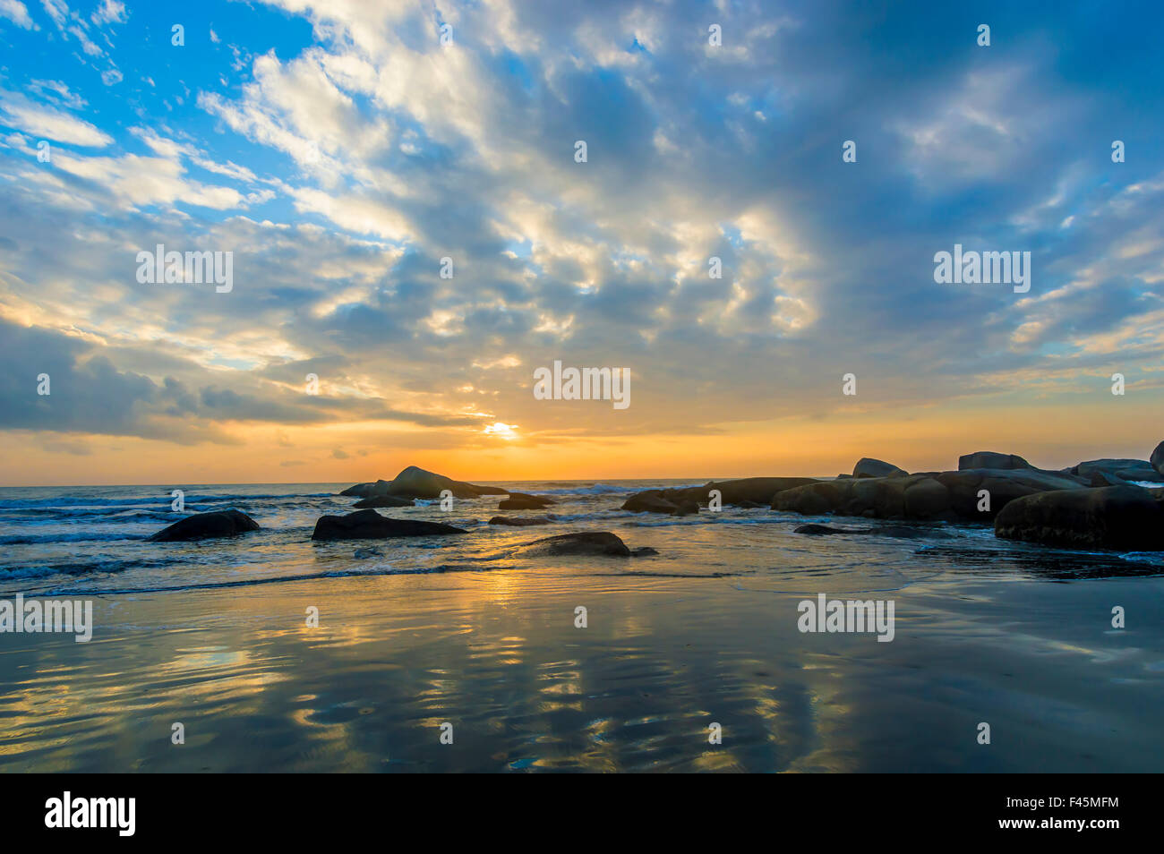 Colorful cloudy sunrise at the beach with reflection and rocks Stock ...