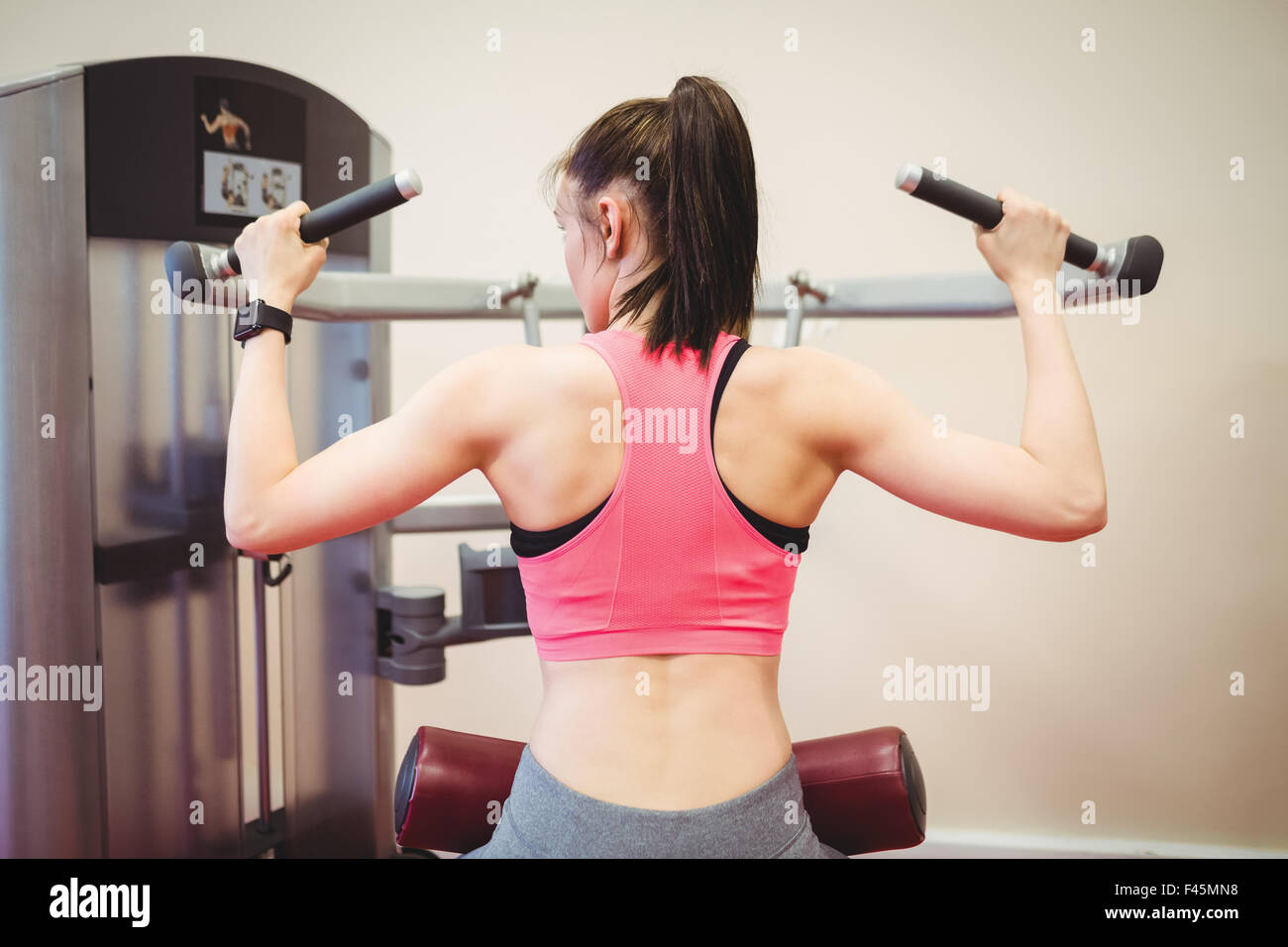 Fit woman using weights machine for arms Stock Photo - Alamy