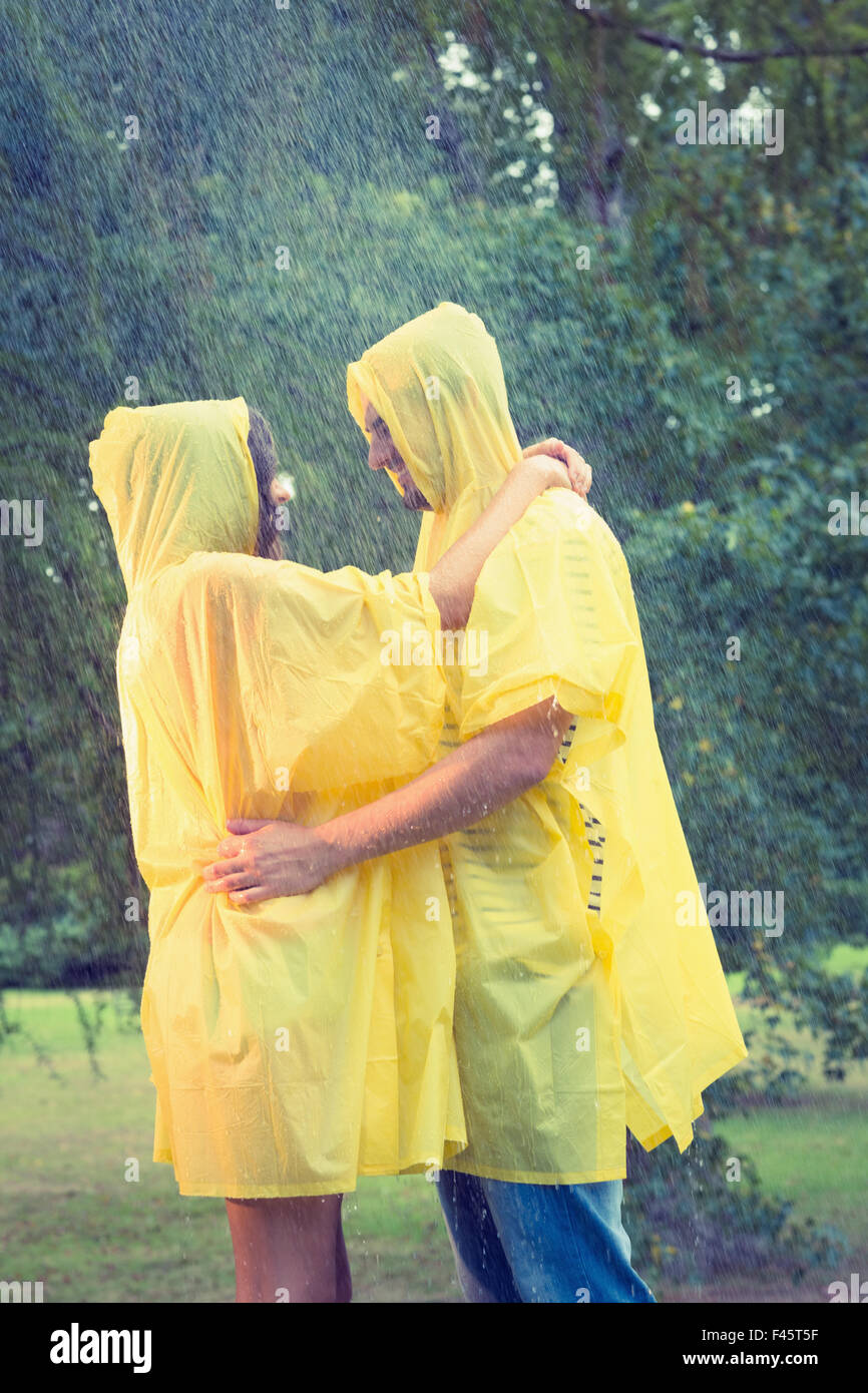 Cute couple wearing protection cape and hugging under the rain Stock ...