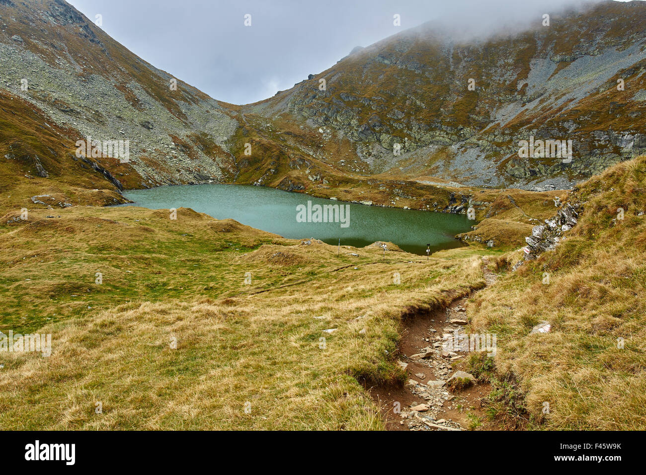 Landscape with a glacial lake in the mist between mountains Stock Photo ...