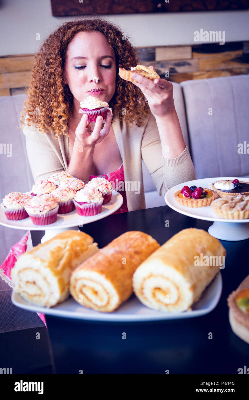 Happy pretty brunette eating a cake Stock Photo - Alamy
