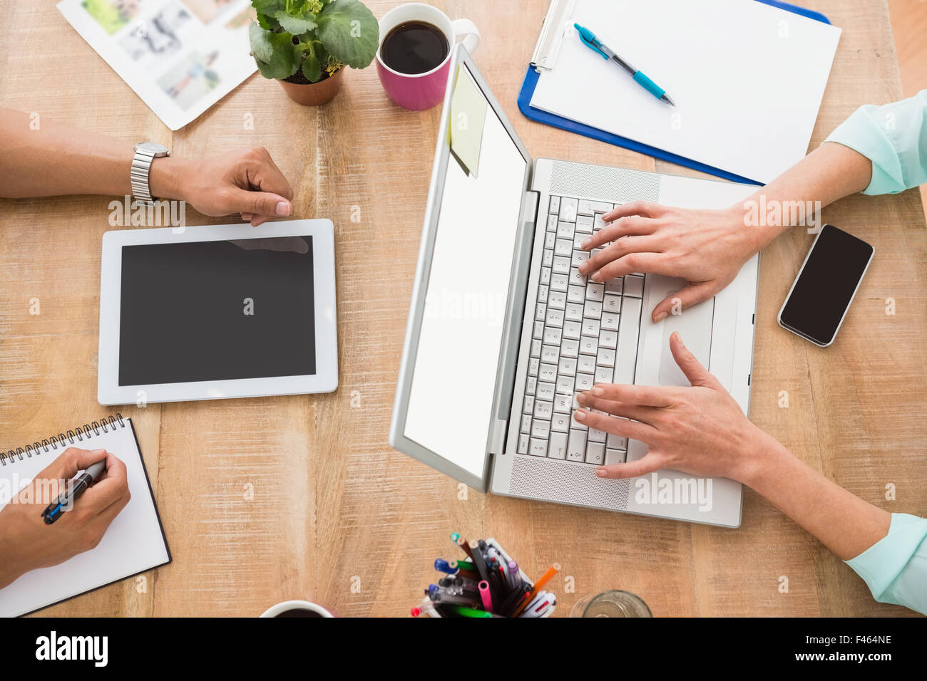 Colleagues using laptop and taking notes Stock Photo - Alamy
