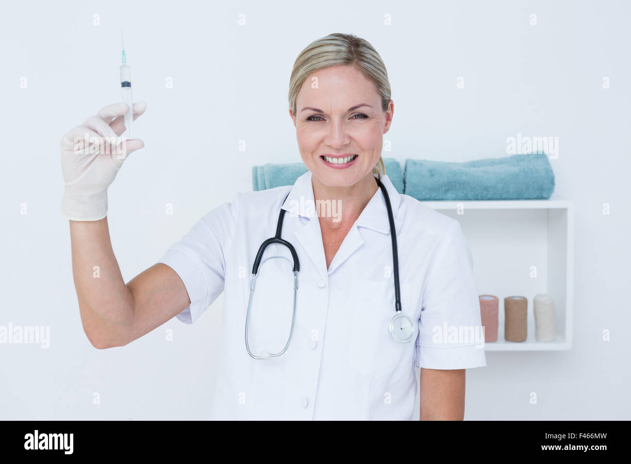 Smiling doctor showing syringe to camera Stock Photo - Alamy