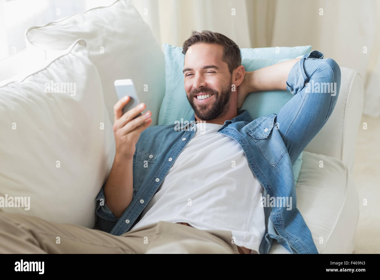 Smiling man sending a text message Stock Photo - Alamy
