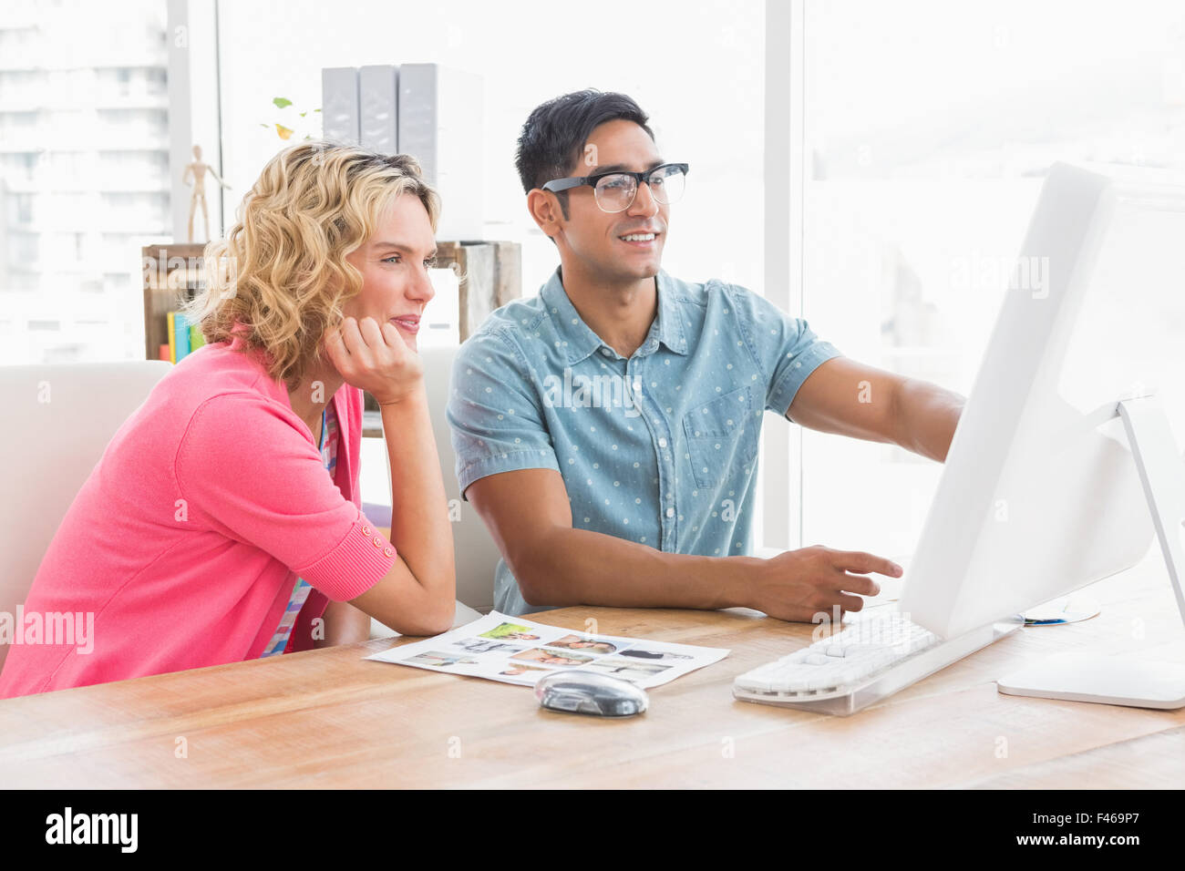 Smiling colleagues working on computer and pointing the screen Stock ...