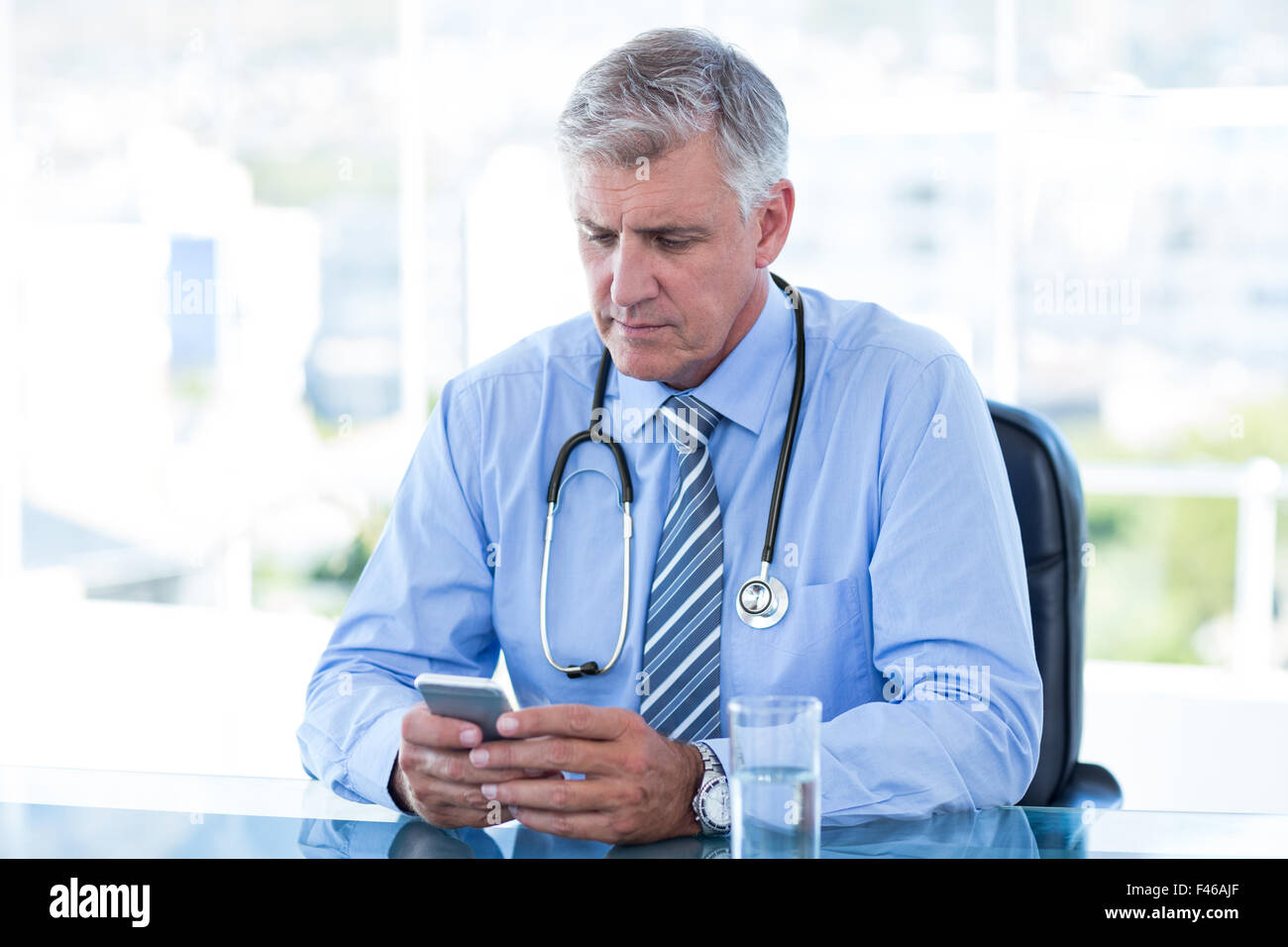 Serious doctor texting with his mobile phone Stock Photo - Alamy