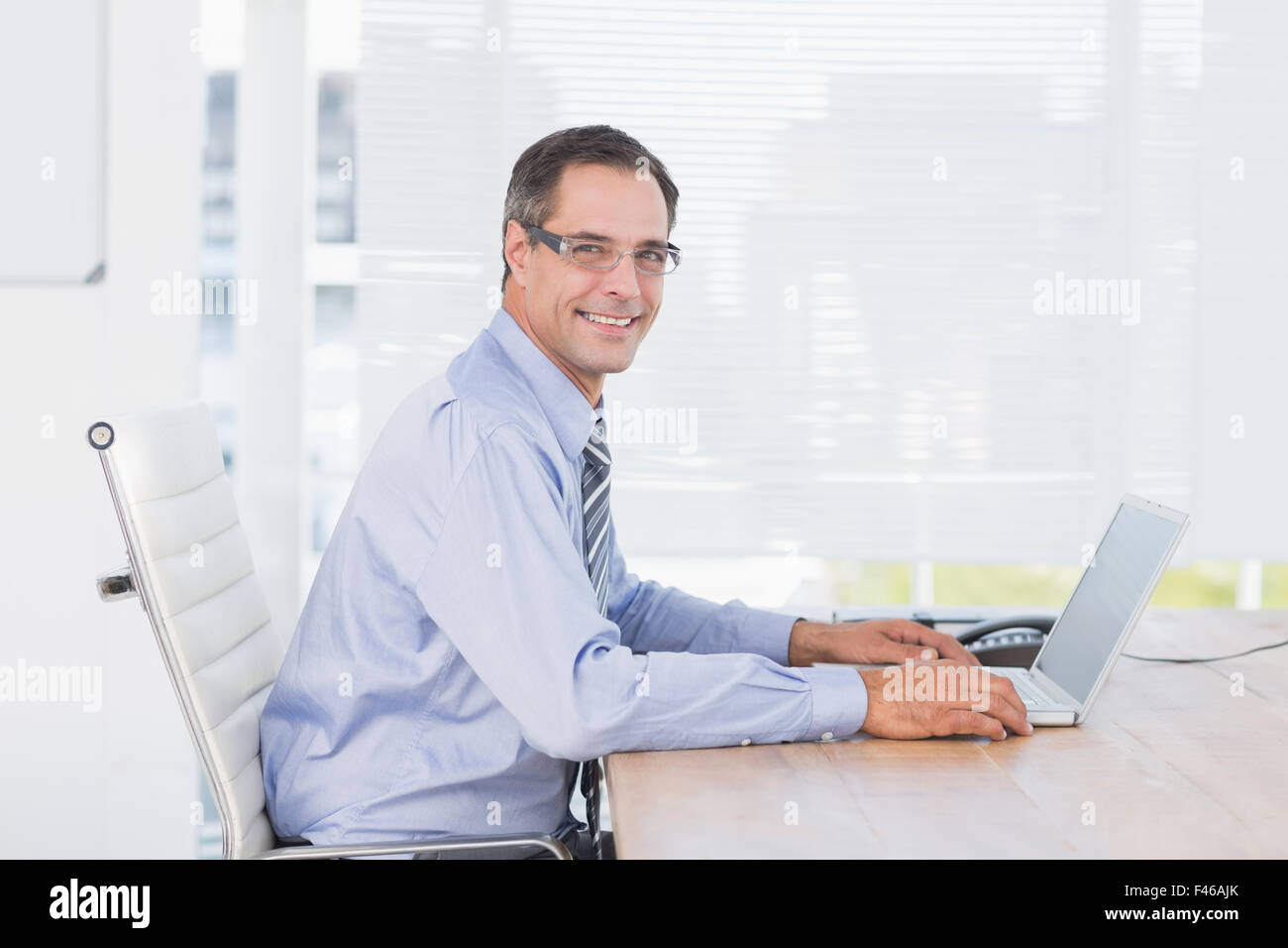 Smiling businessman using his computer Stock Photo - Alamy