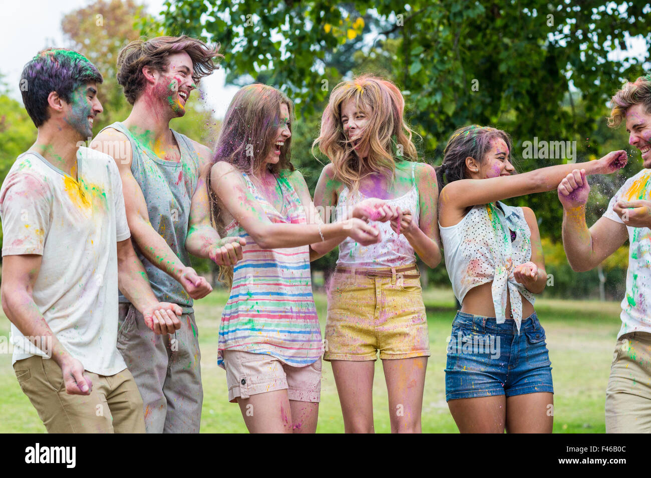 Happy friends throwing powder paint Stock Photo - Alamy