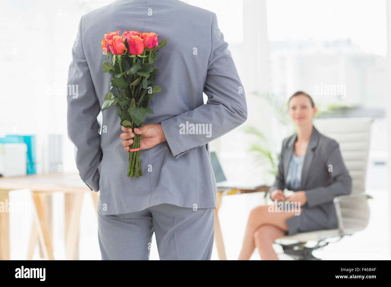 Businessman holding flowers behind his back Stock Photo - Alamy