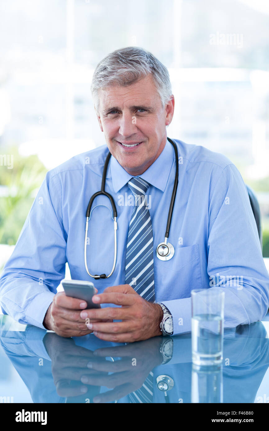 Smiling doctor texting with his mobile phone Stock Photo - Alamy