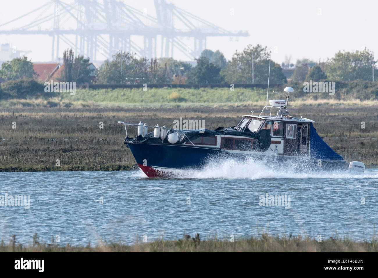 A motor boat on Benfleet creek with the Canvey Island cranes in the ...