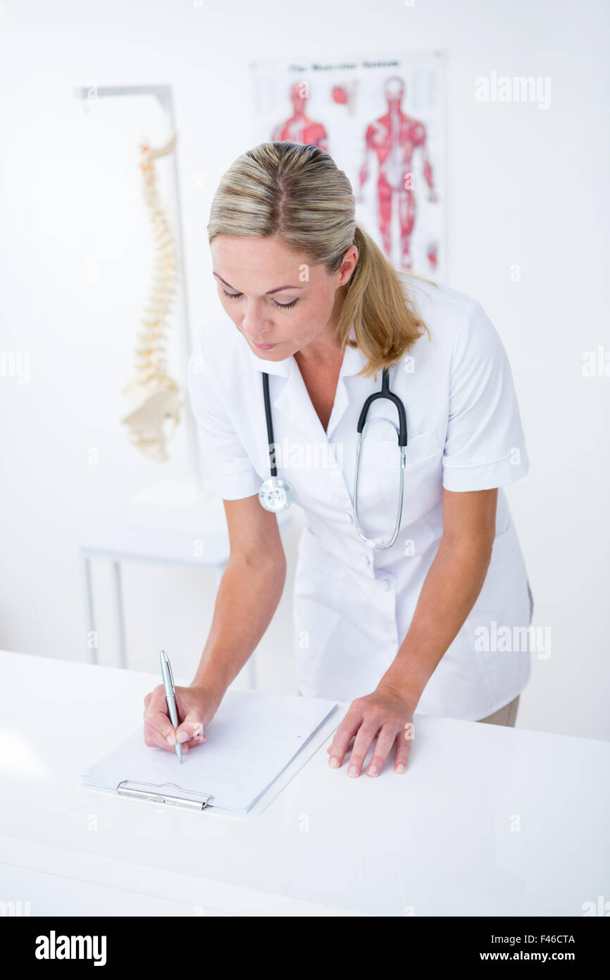 Doctor writing on clipboard at her desk Stock Photo - Alamy