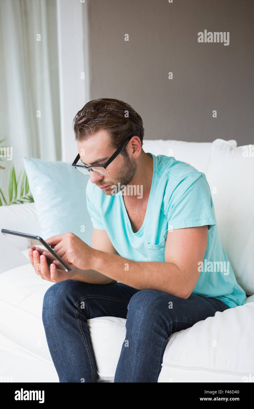 Concentrated handsome man using tablet on couch Stock Photo - Alamy