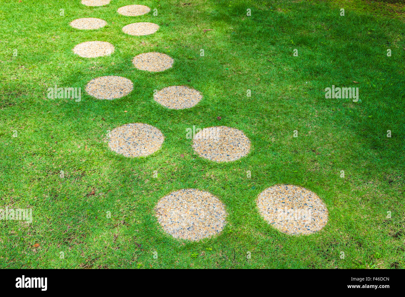 Stone wash pebble path on green grass Stock Photo - Alamy