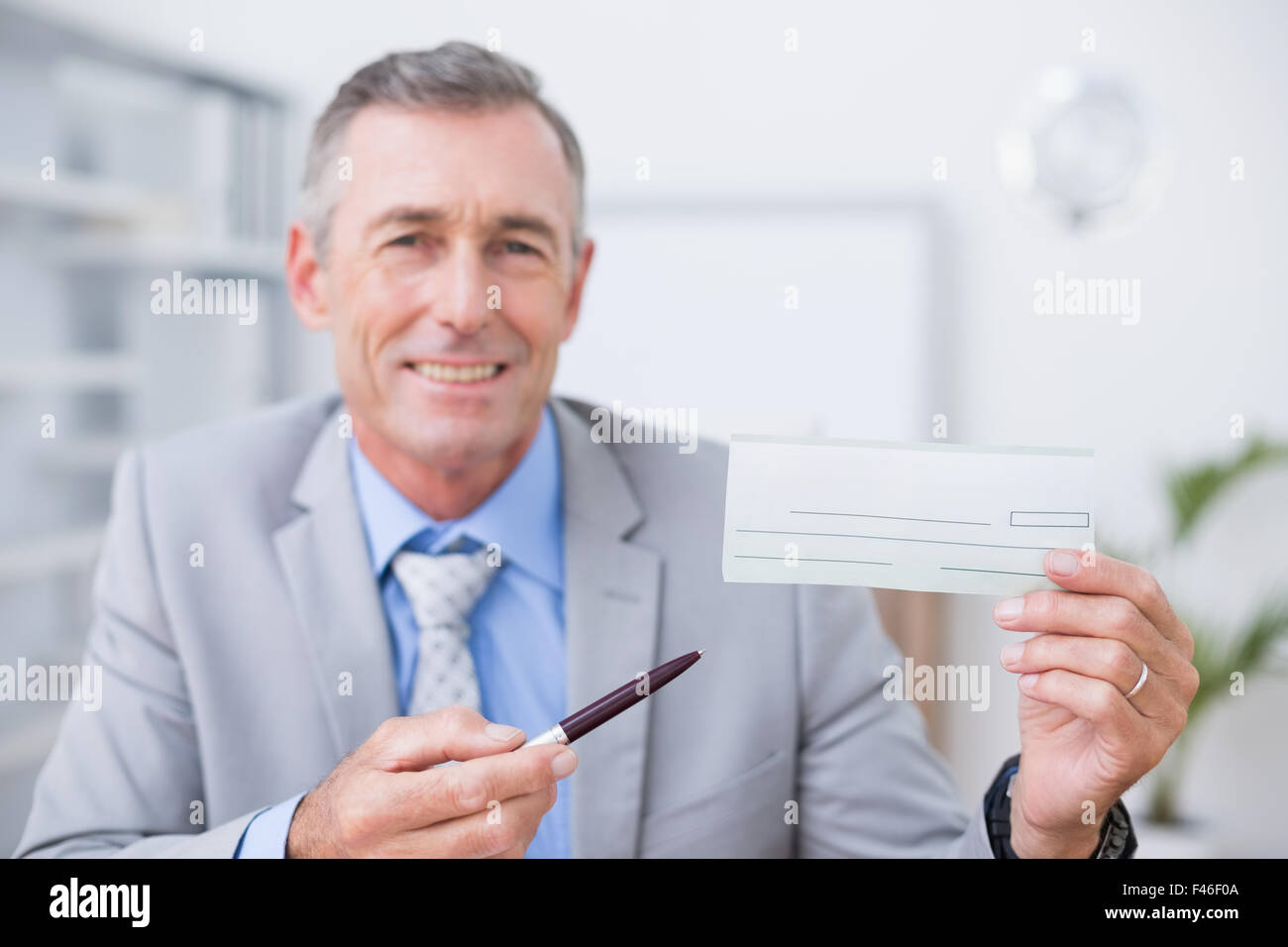 Smiling businessman holding cheque Stock Photo - Alamy