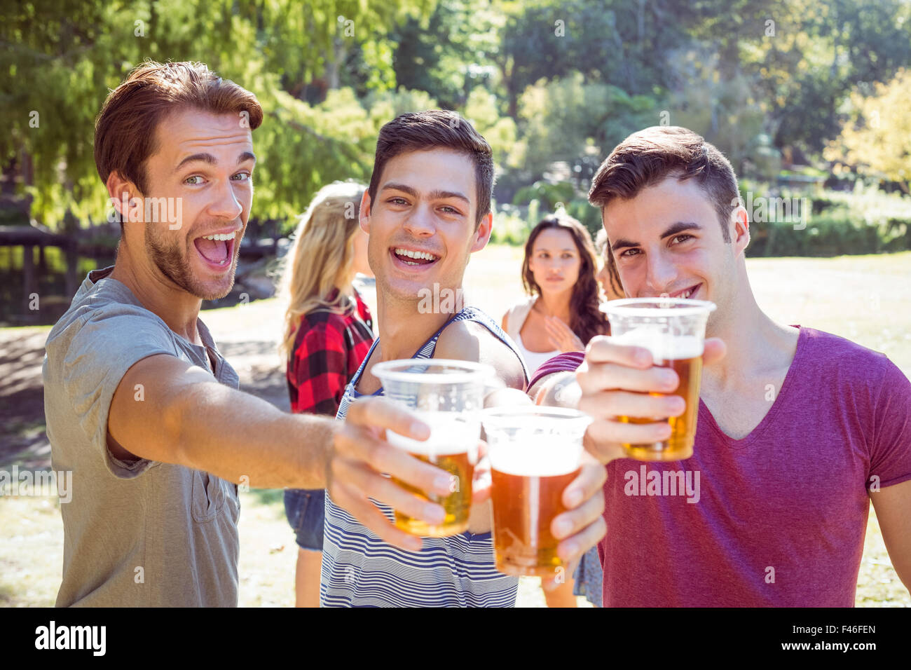 Happy friends in the park having beers Stock Photo - Alamy