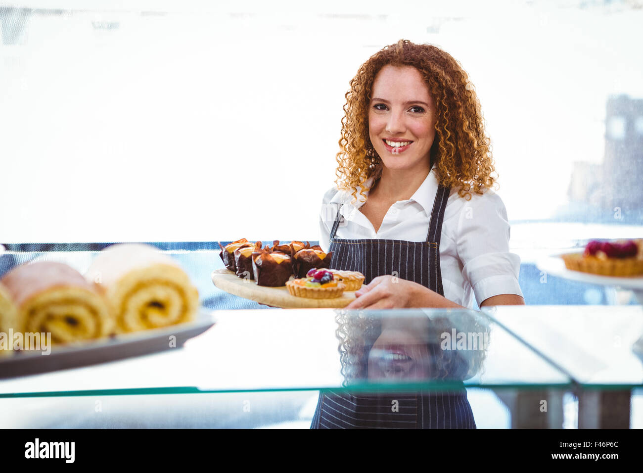 Pretty barista holding plate with cakes Stock Photo - Alamy